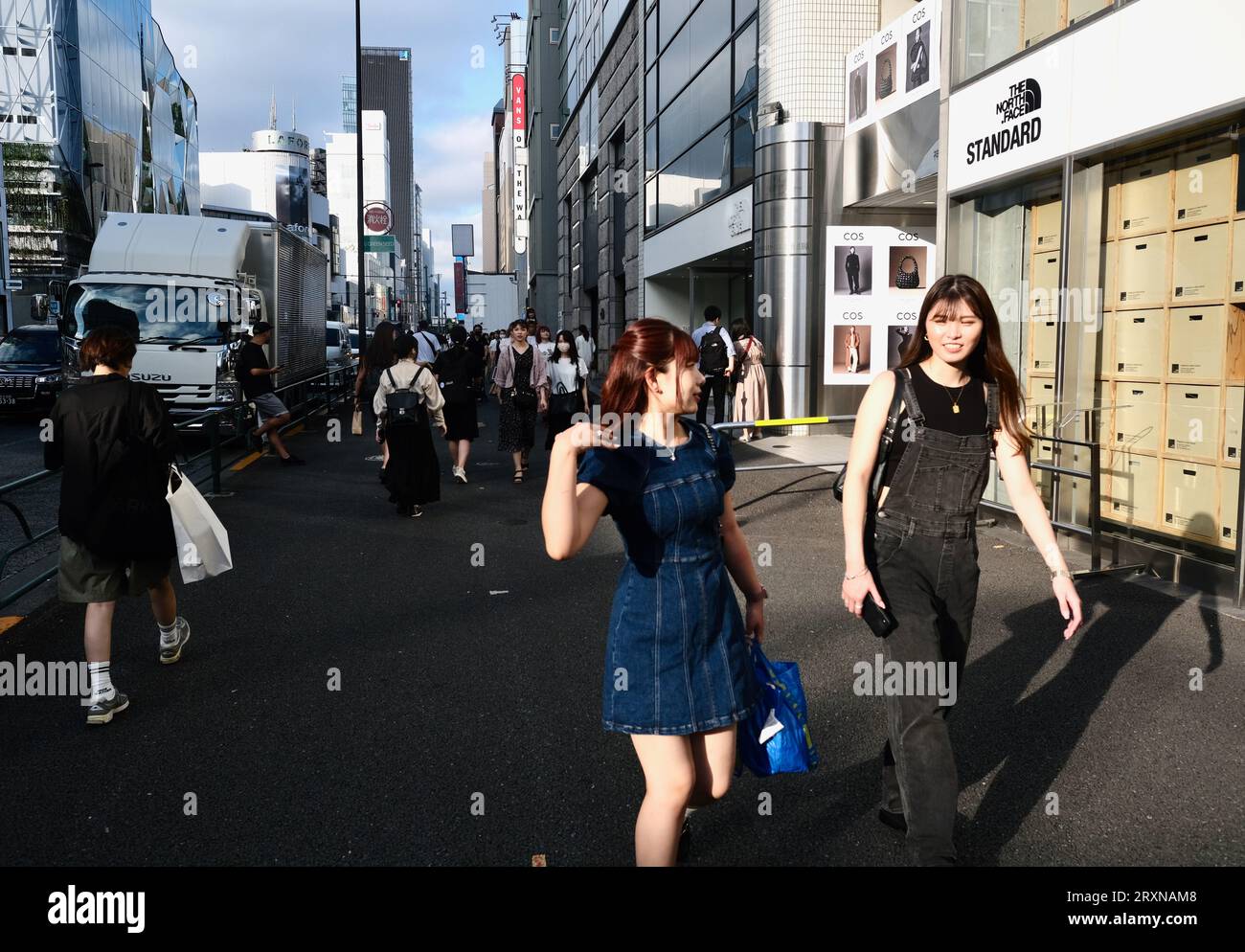 Two women walk along the pavement in the high-end shopping district of ...