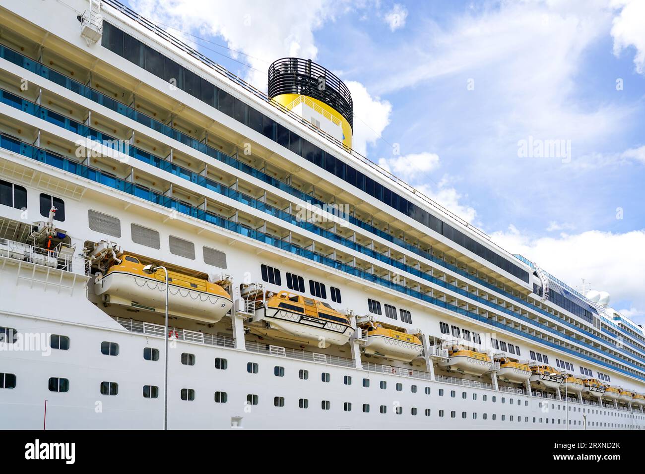 Side view of a large white cruise ship with many hanging lifeboats and ...