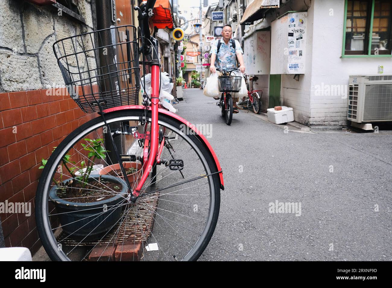 A male cyclist ridesi his bike in the Golden Gai are of Shinjuku, Tokyo ...