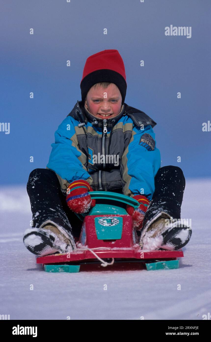 Little young girl sitting on sledge, bobsleigh, snow, winter ...