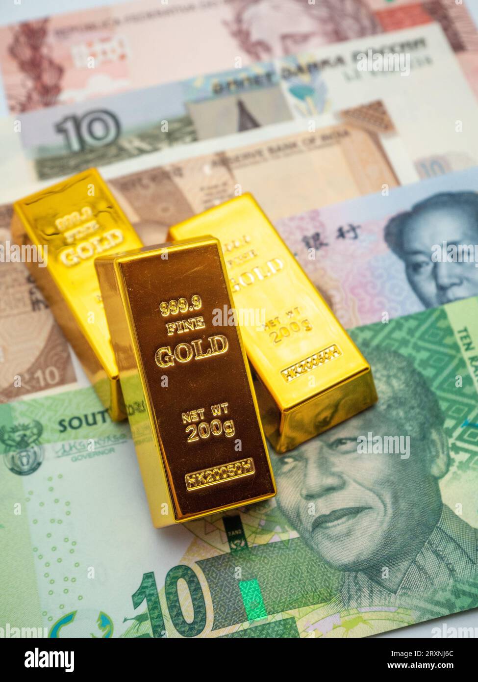 golden bullion on the surface with different brics currency banknotes ...