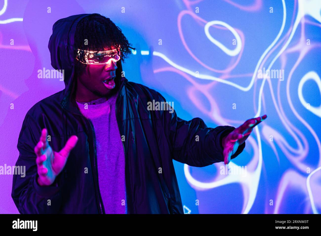 Studio portrait with purple and blue neon lights of a shocked afro man ...