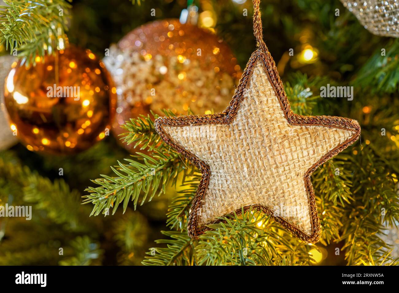 selective focus on a burlap star ornament on a decorated holiday tree ...
