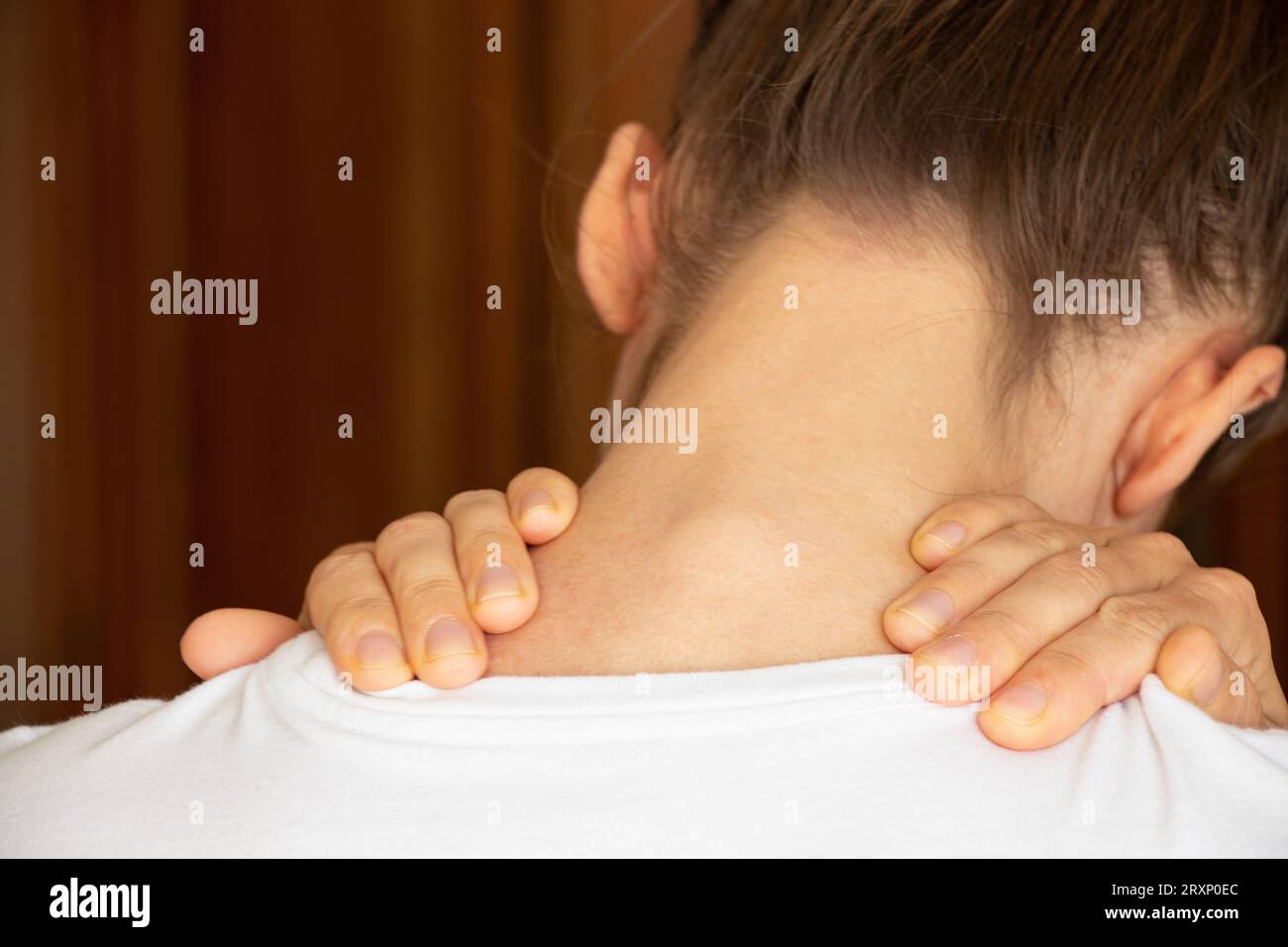 A girl holds her hands behind her neck at home, sore neck, acute pain ...