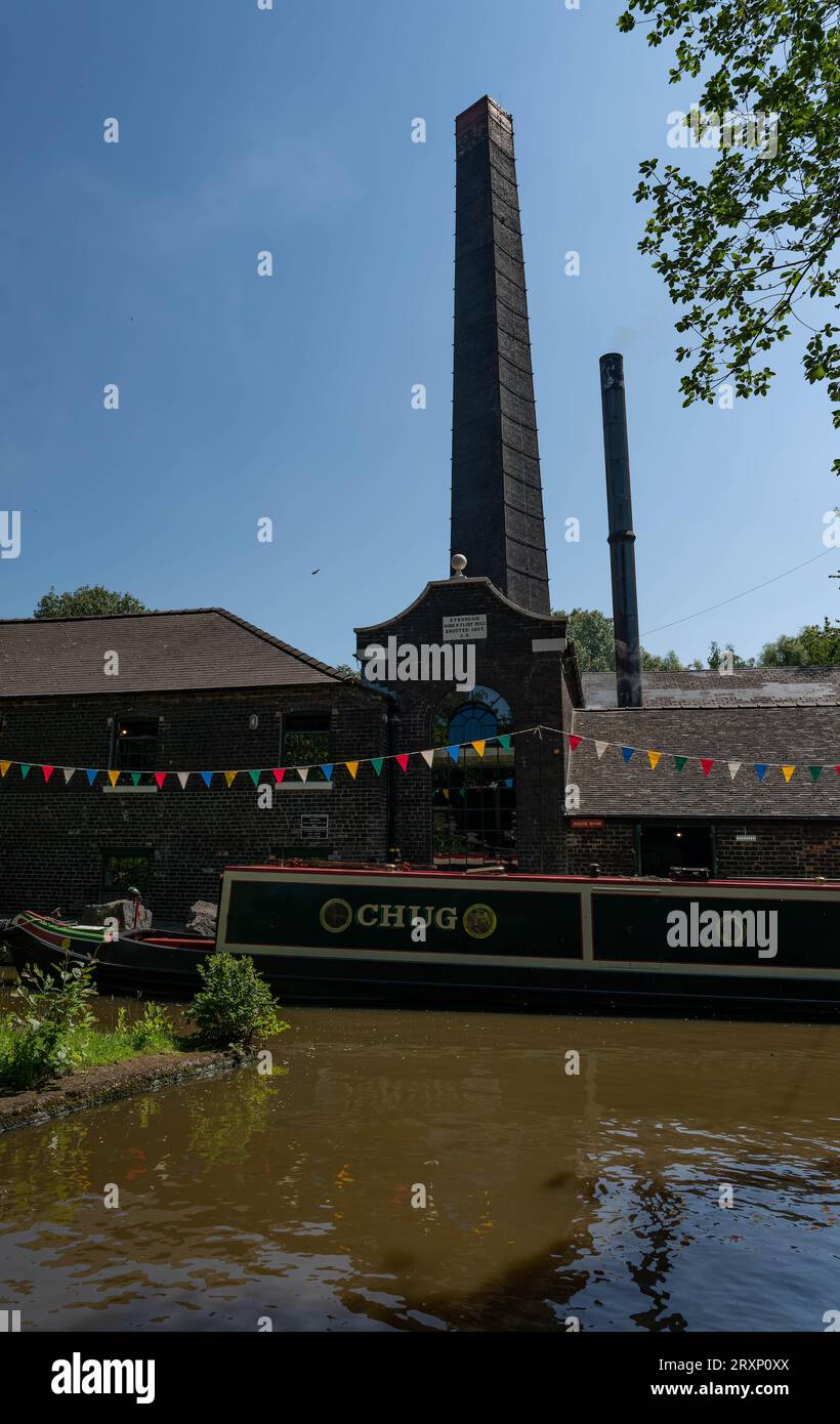 Historic brick mill chimney with narrowboat on canal and colourful ...