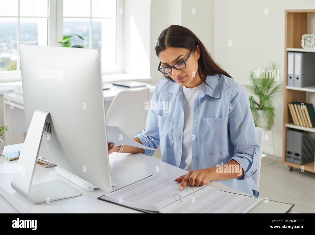 Female accountant looking though business documents at office desk with ...
