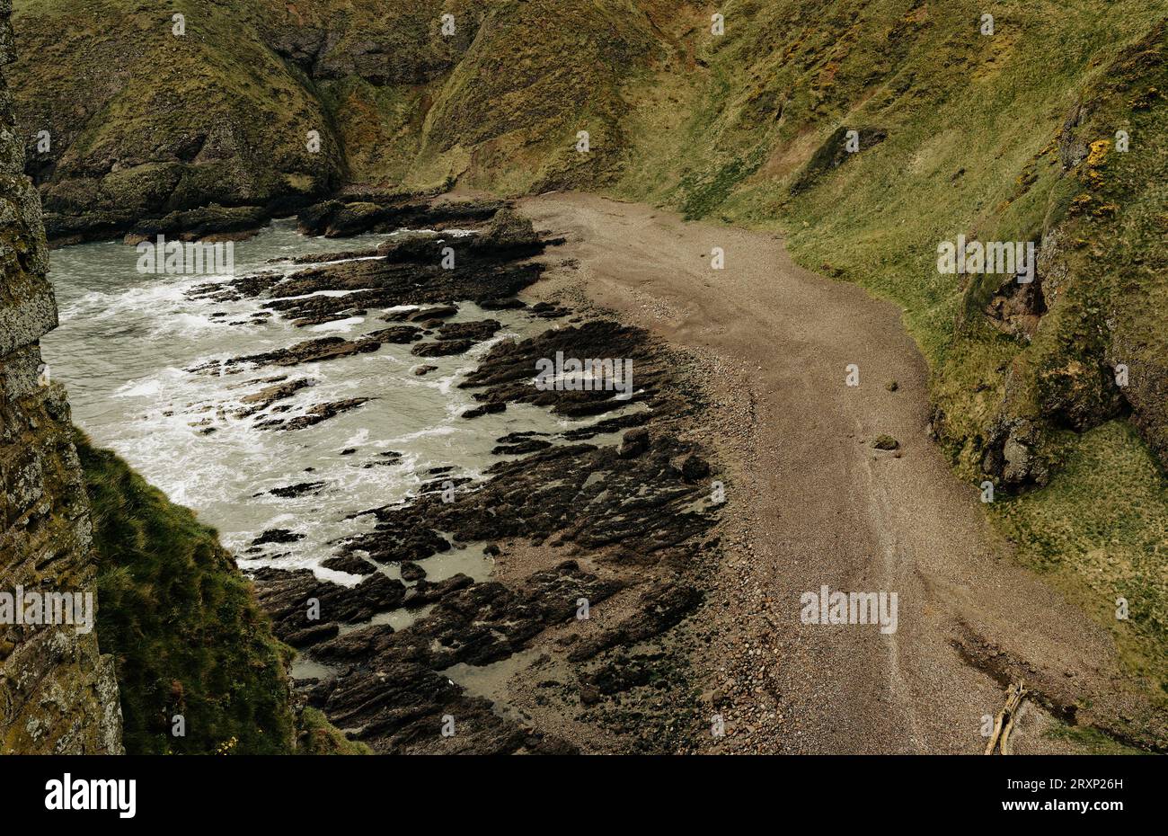 Secluded Scottish beach cove with rocky outcrops and green clifftops ...