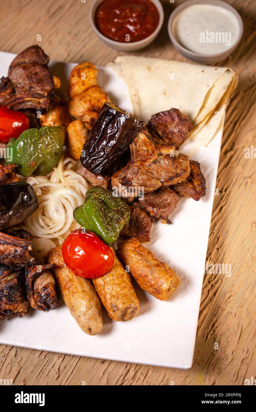 top view of a delicious fresh kebab of different meats with sauce close ...