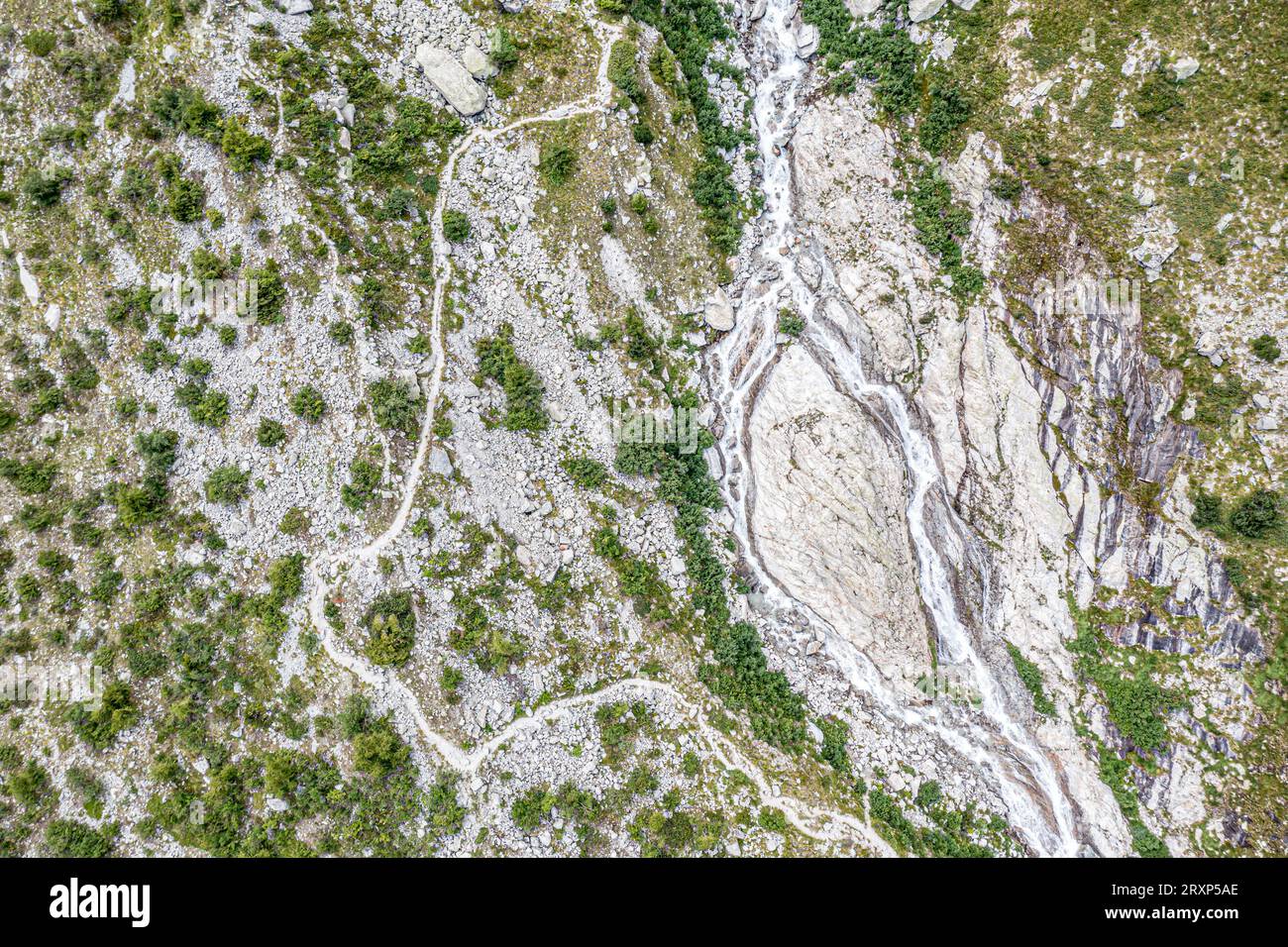 Aerial view, glacial stream flows around a large rock, hiking path from ...