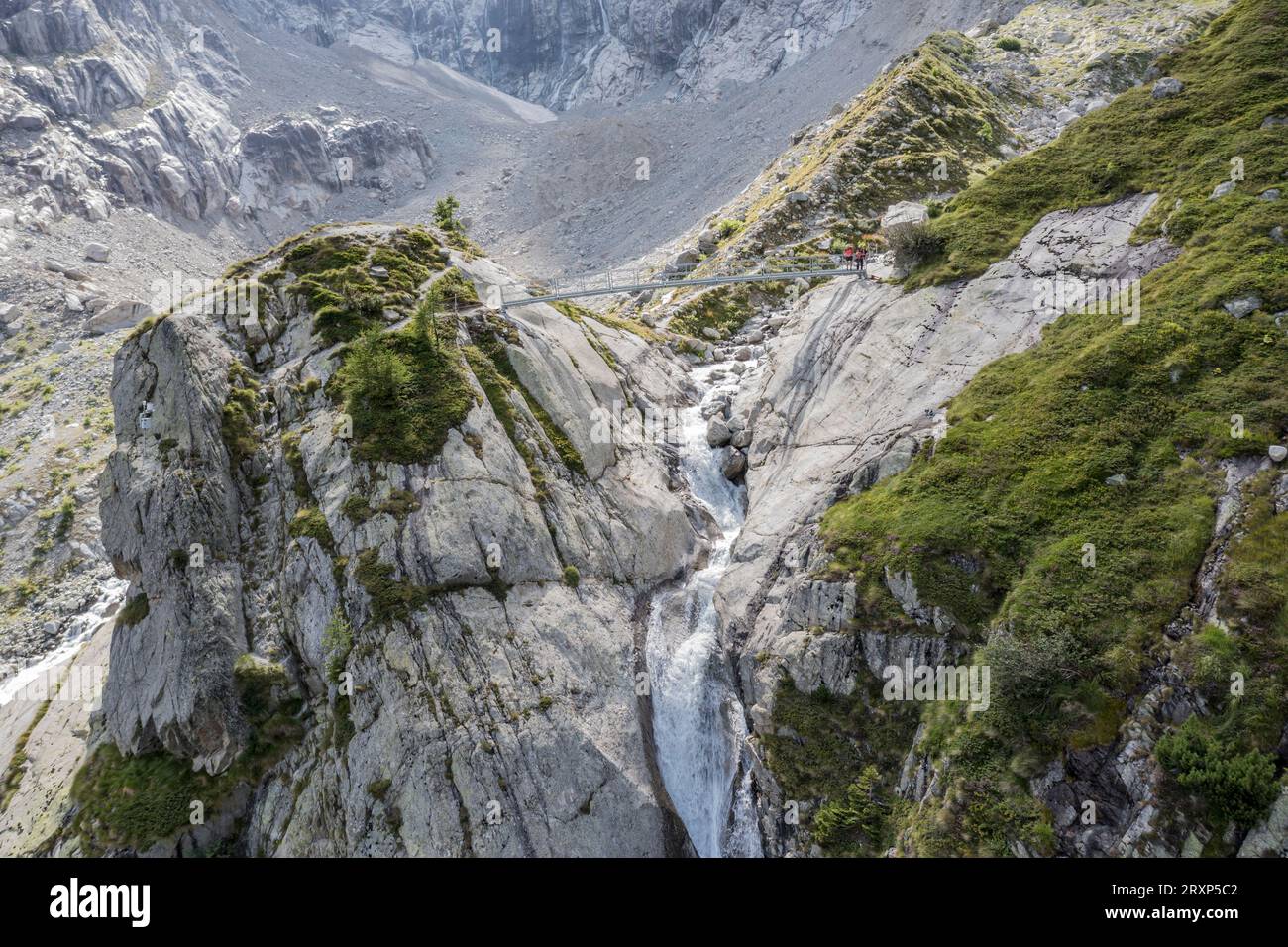 Aerial view, hikers at bridge over glacial stream, large single rock ...