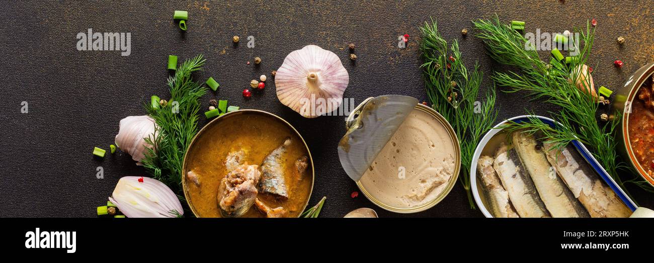 Different open tin cans with canned fish among spices and herbs banner ...