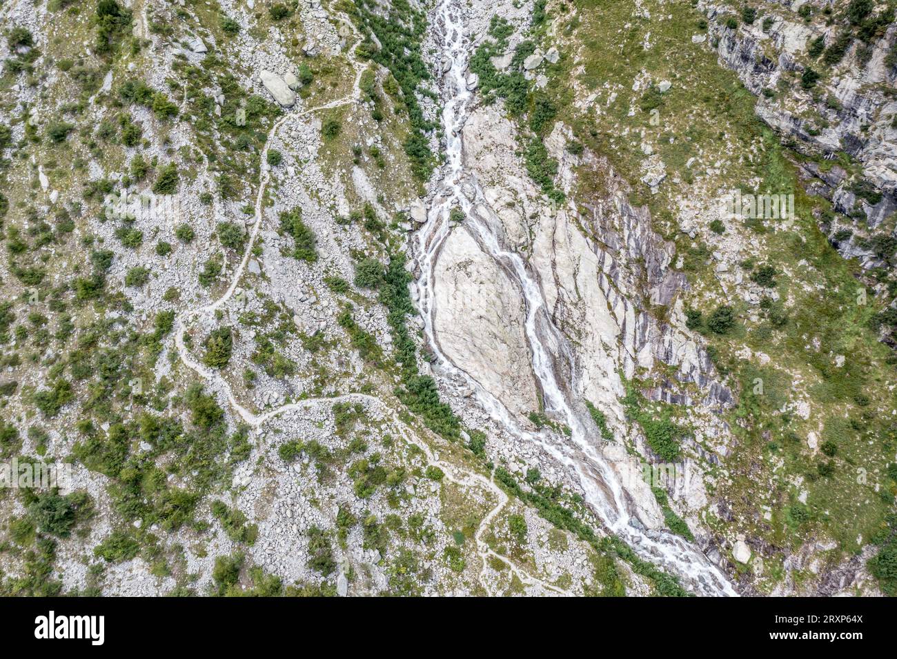 Aerial view, glacial stream flows around a large rock, hiking path from ...