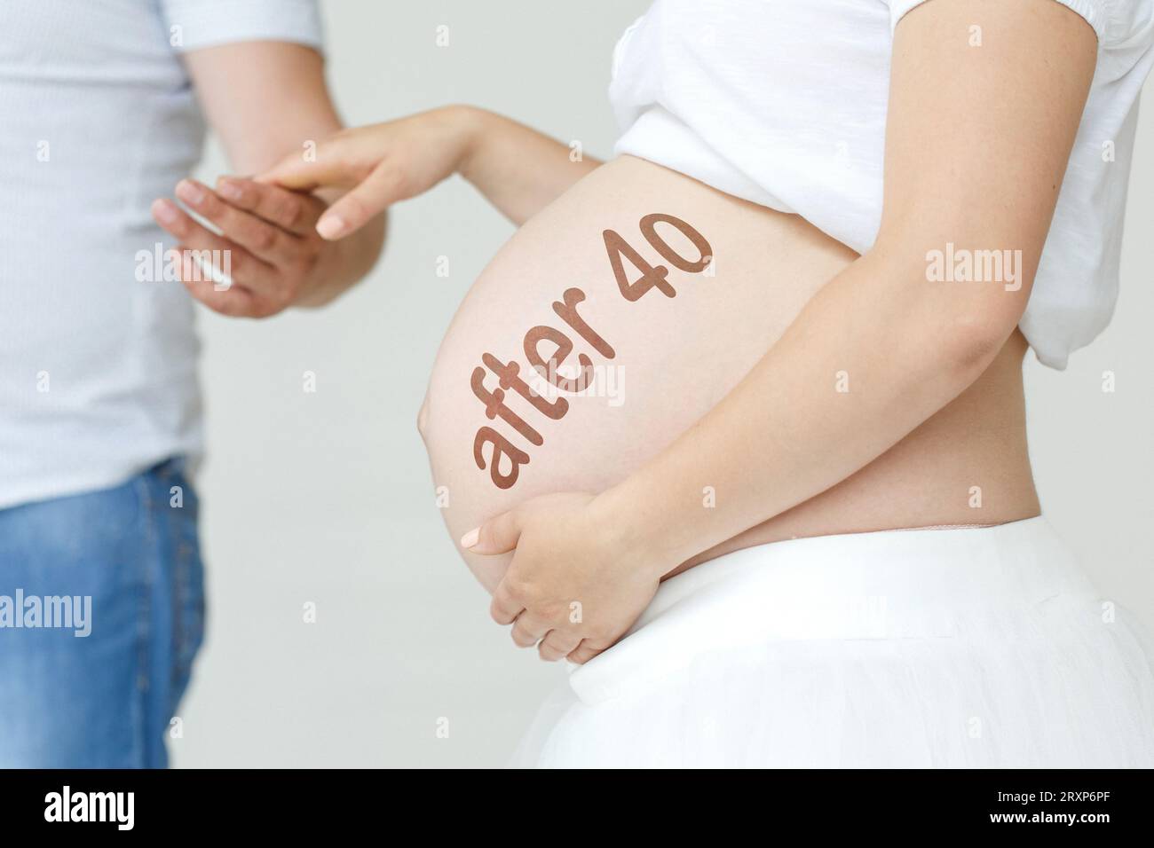 A pregnant woman holds her husband's hand on her stomach with the ...