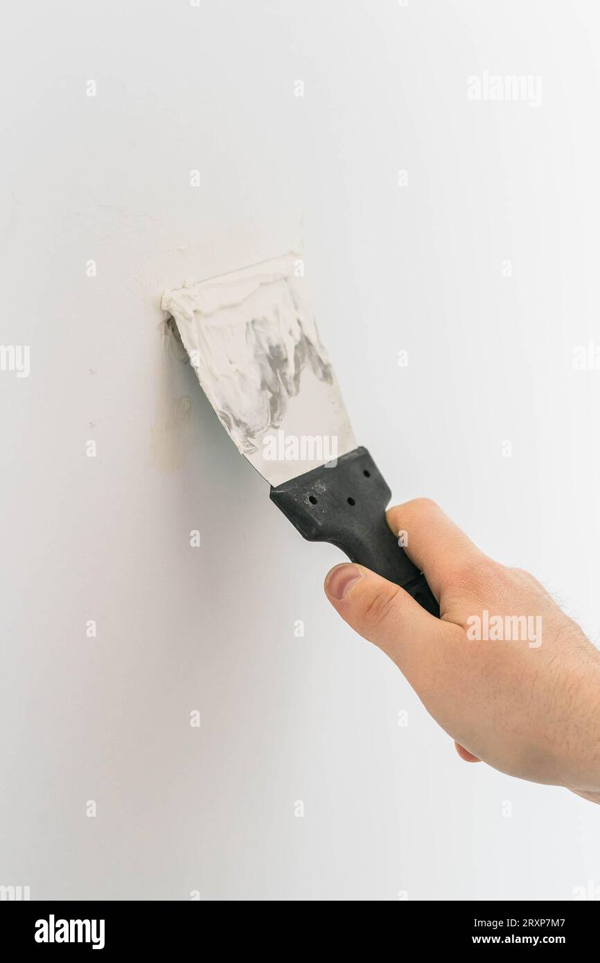Male using spatula and plastering of wall with white fresh finishing ...
