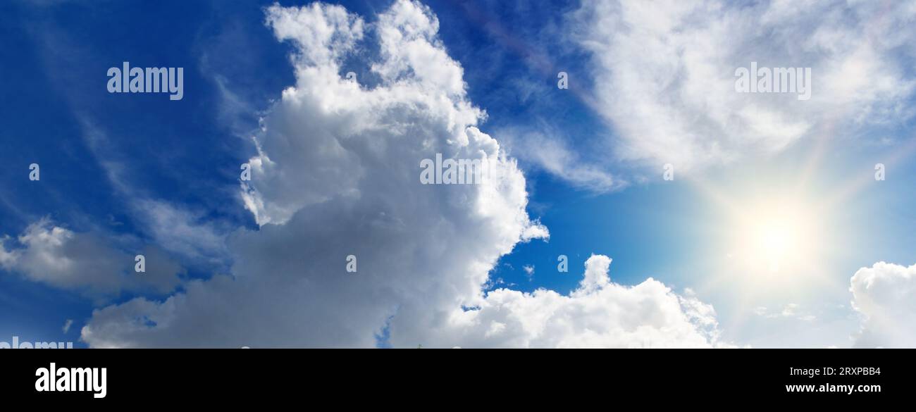 Blue sky, cumulus clouds and sun. Wide photo Stock Photo - Alamy