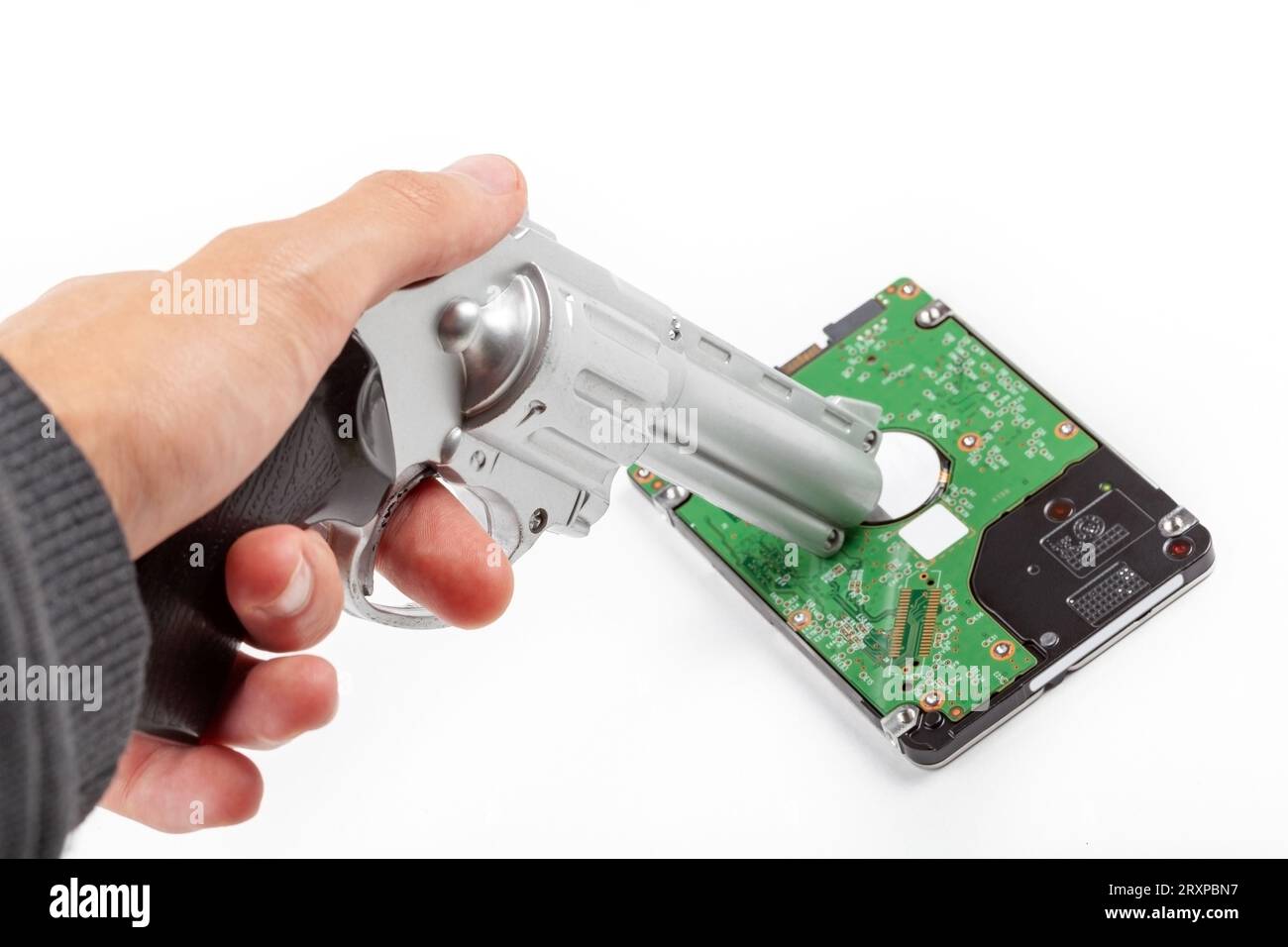 Man, hand holding a HDD disk drive at gunpoint, silver revolver aiming ...