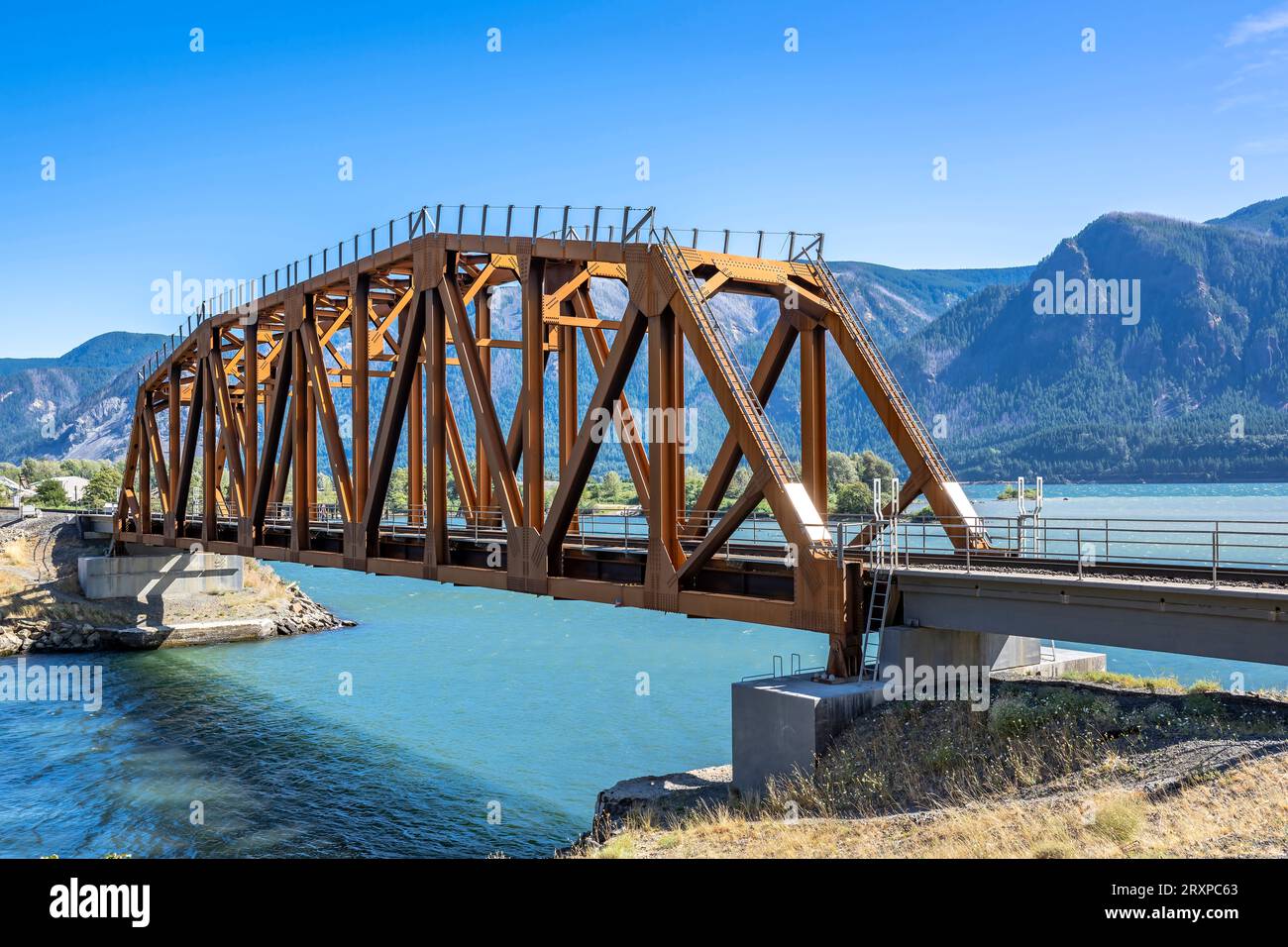 Rusty narrow metal truss railway transportation bridge across Columbia ...