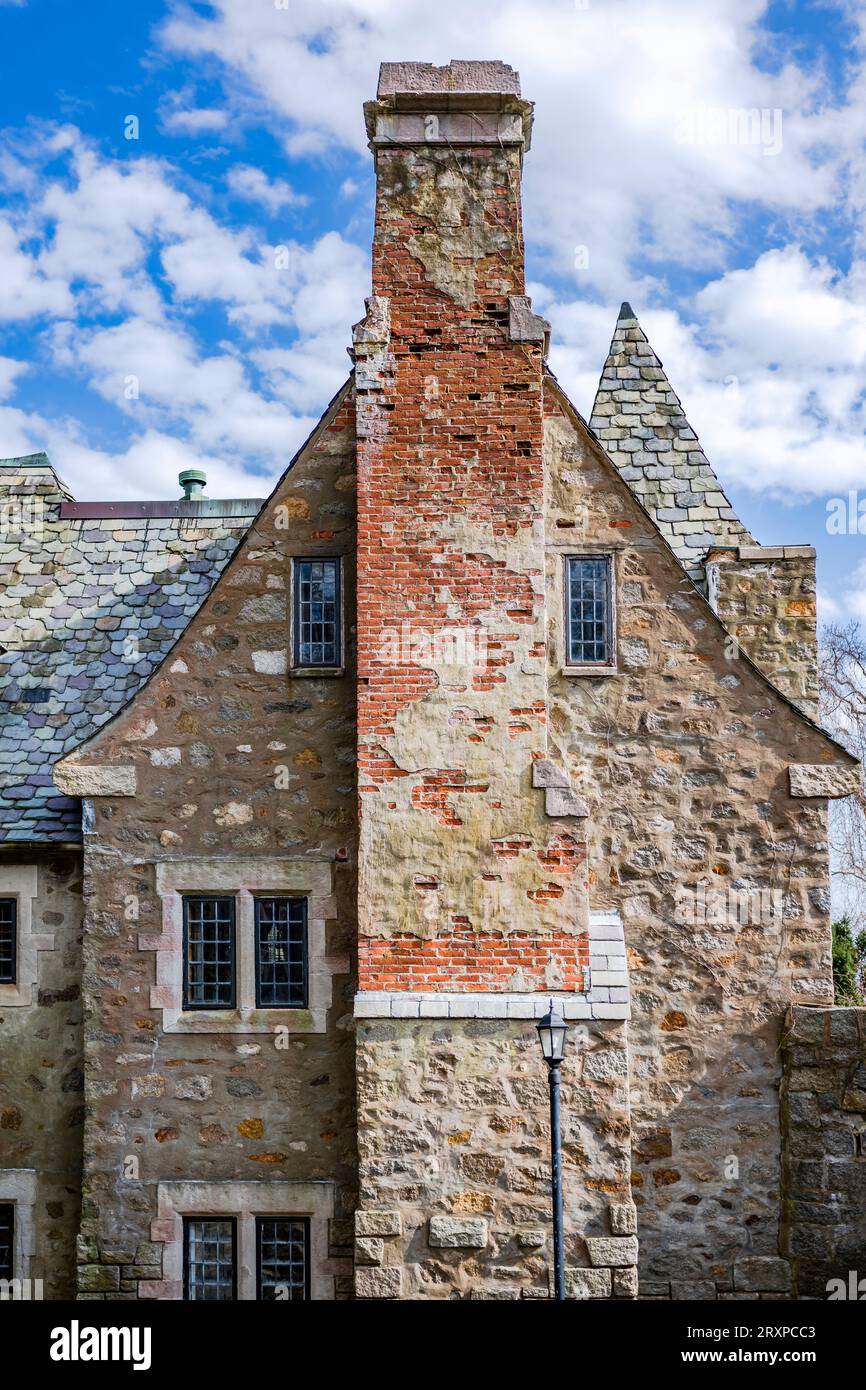 An old peeling three-story stone house with a red brick chimney and a ...
