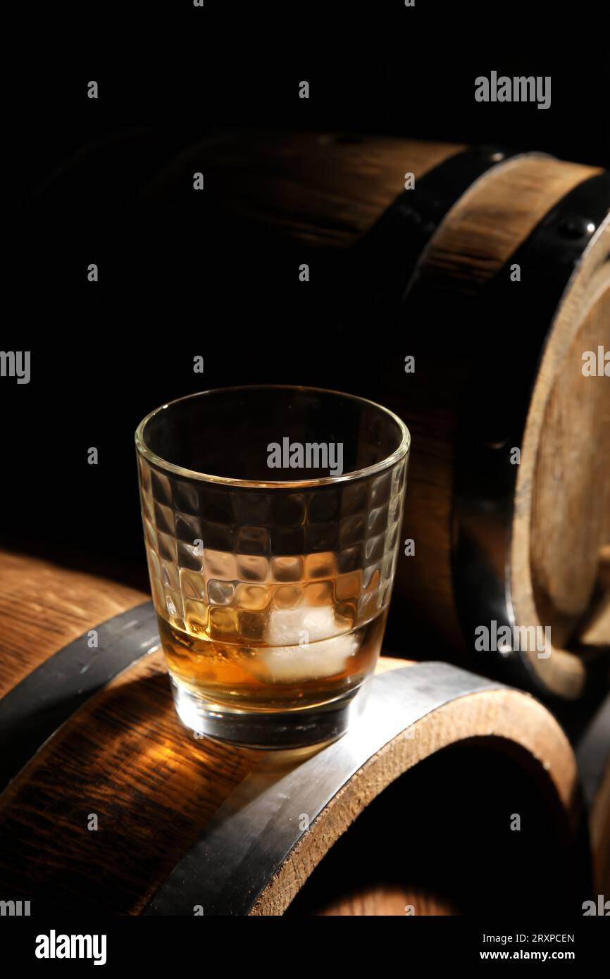 Glass of cold whiskey with wooden barrels on dark background Stock ...