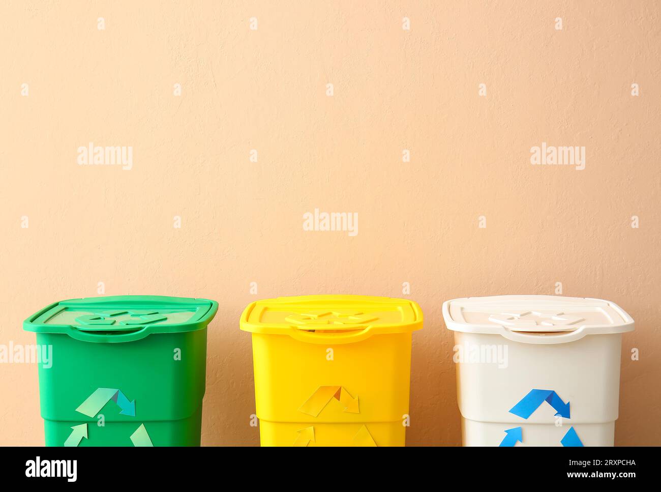 Different garbage bins with recycling symbol near beige wall Stock ...