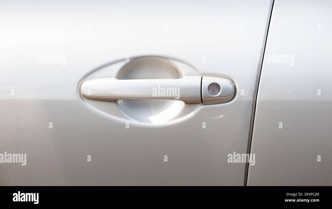 Simple generic silver car door handle with a key lock hole, side front ...