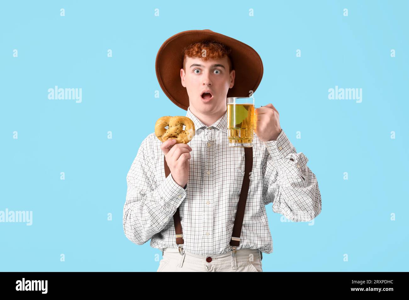 Shocked young man in traditional German clothes with beer and pretzel ...