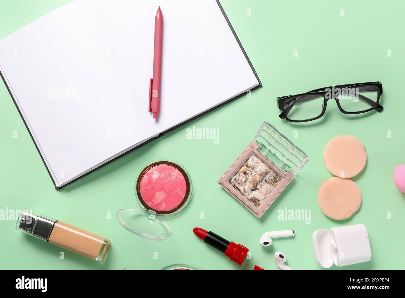 Composition with makeup cosmetics, eyeglasses and notebook on green ...