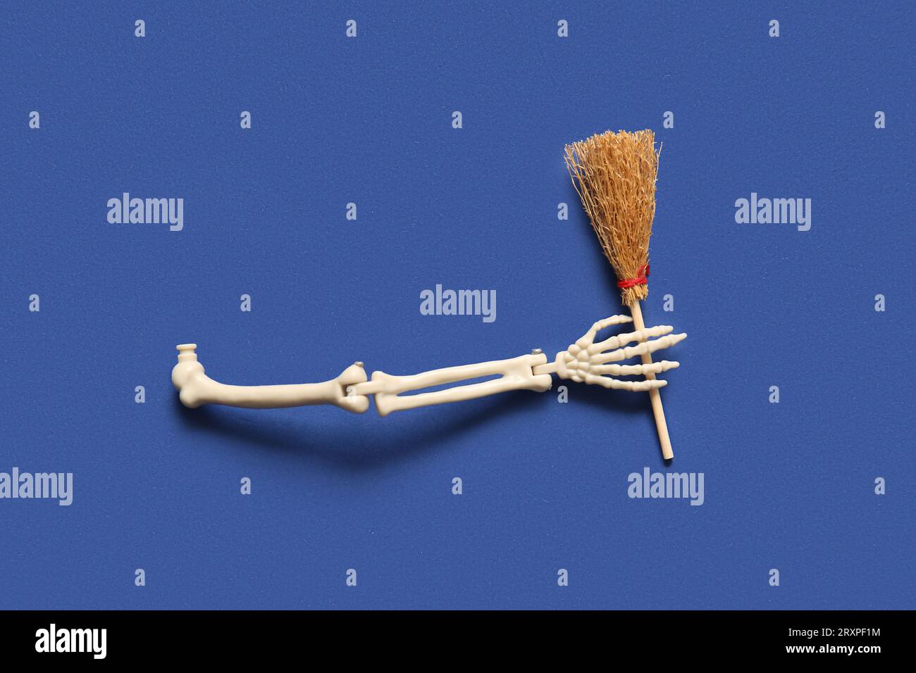 Halloween skeleton hand with broom on blue background Stock Photo - Alamy