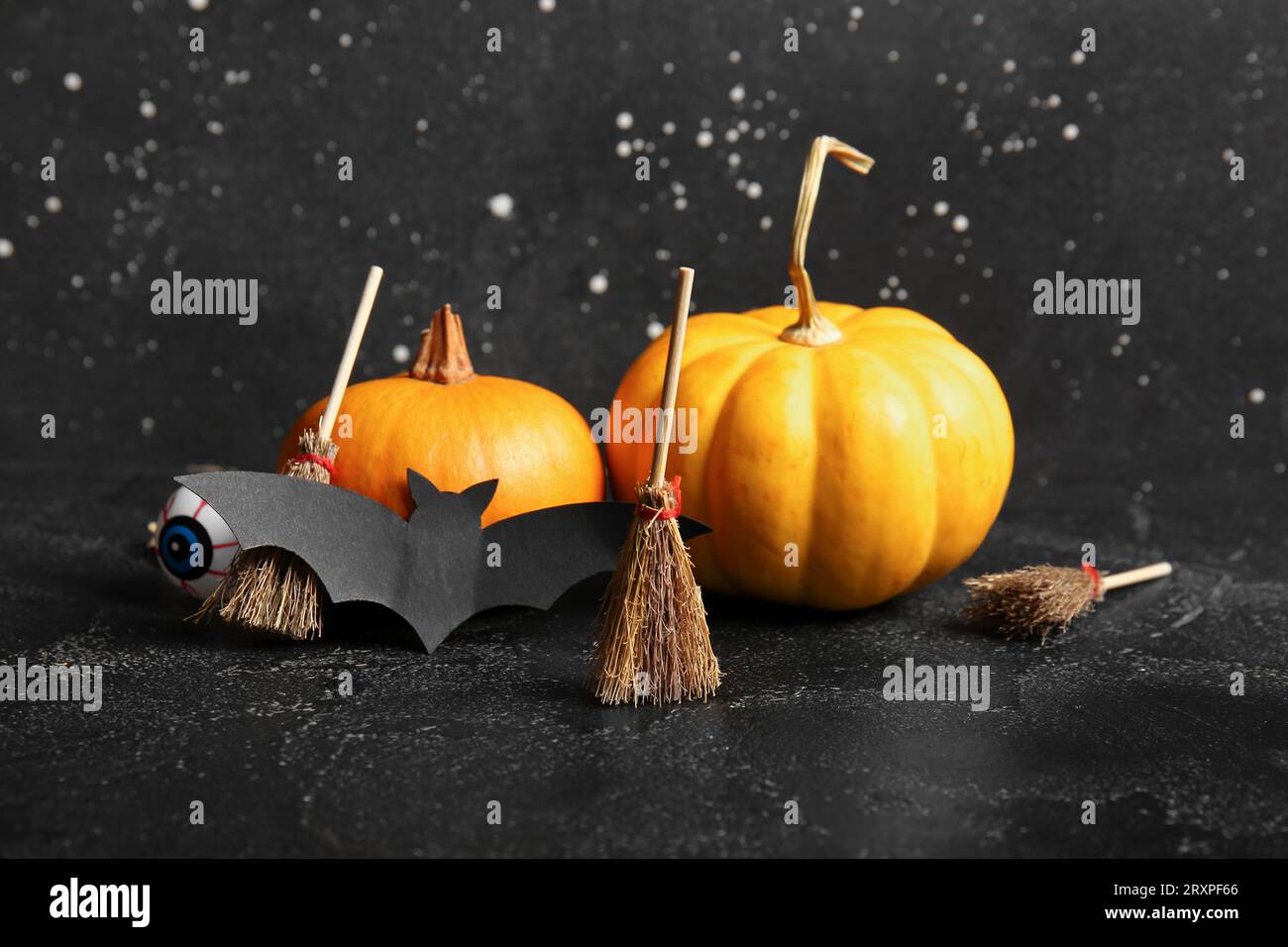 Halloween composition with brooms, pumpkins and bat on black grunge ...