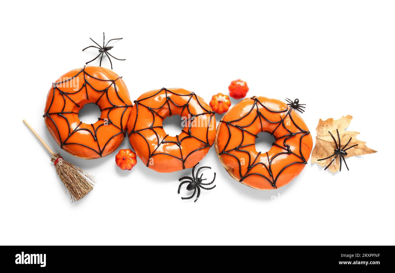 Tasty donuts for Halloween with candies, leaves and broom on white ...