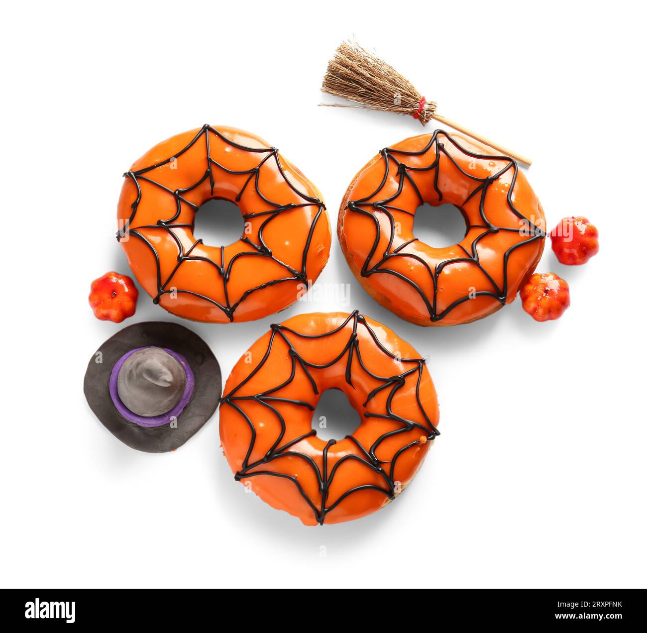 Tasty donuts for Halloween with witch hat, candies and broom on white ...