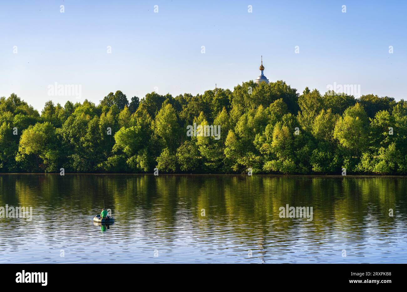 A fisherman on an inflatable rubber boat is fishing opposite an island ...