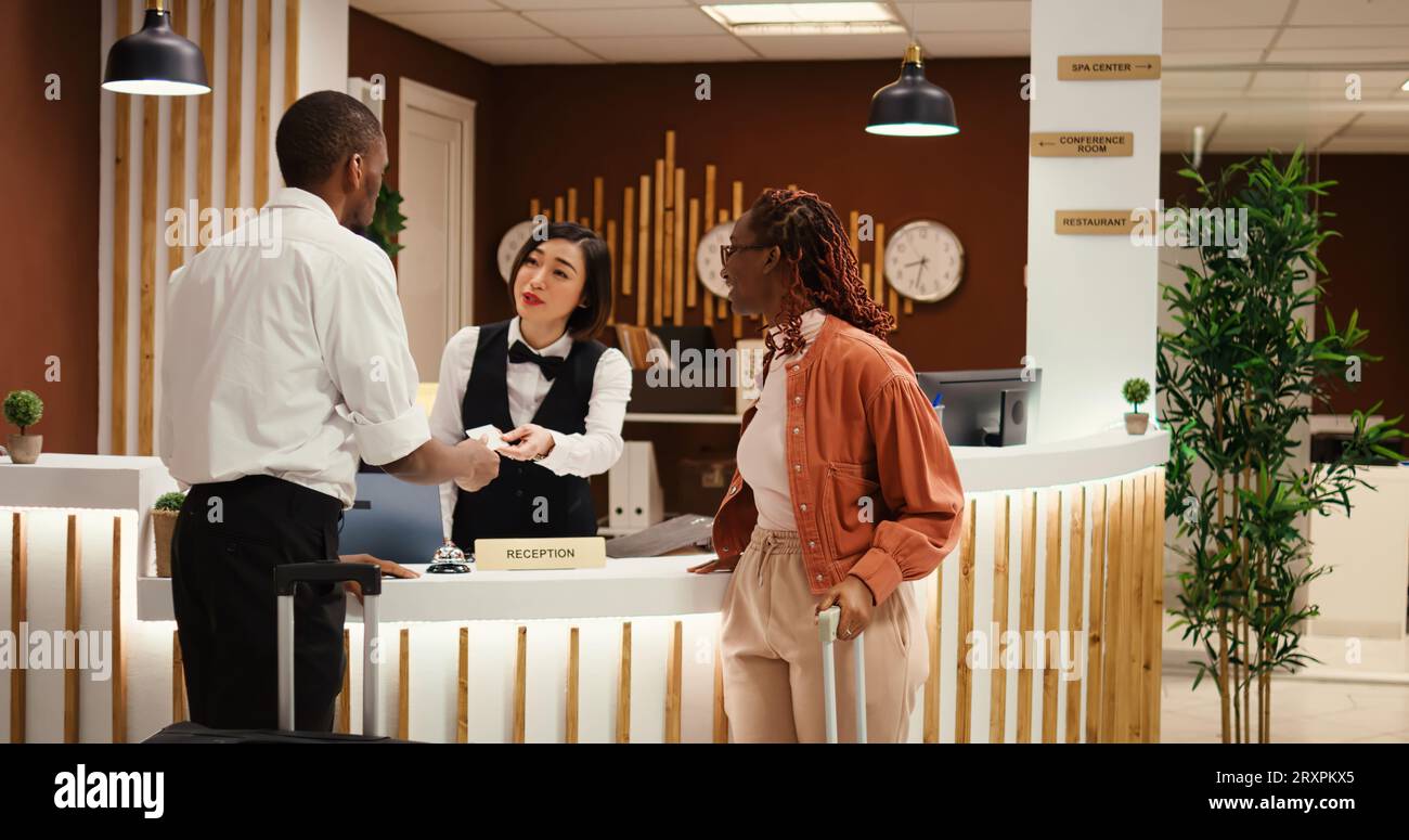 Friendly bellhop employee showing tourists the way to their room while ...