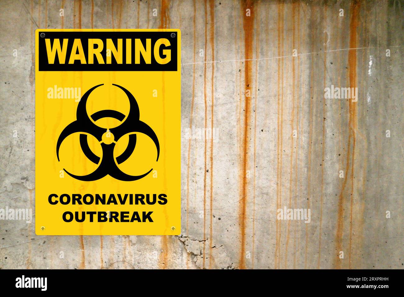 Yellow warning sign screwed to a concrete wall to warn about a threat ...