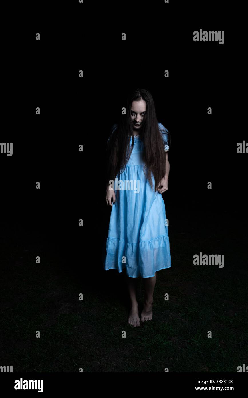 a scary girl in a blue dress is standing in the dark.a terrible drowned ...