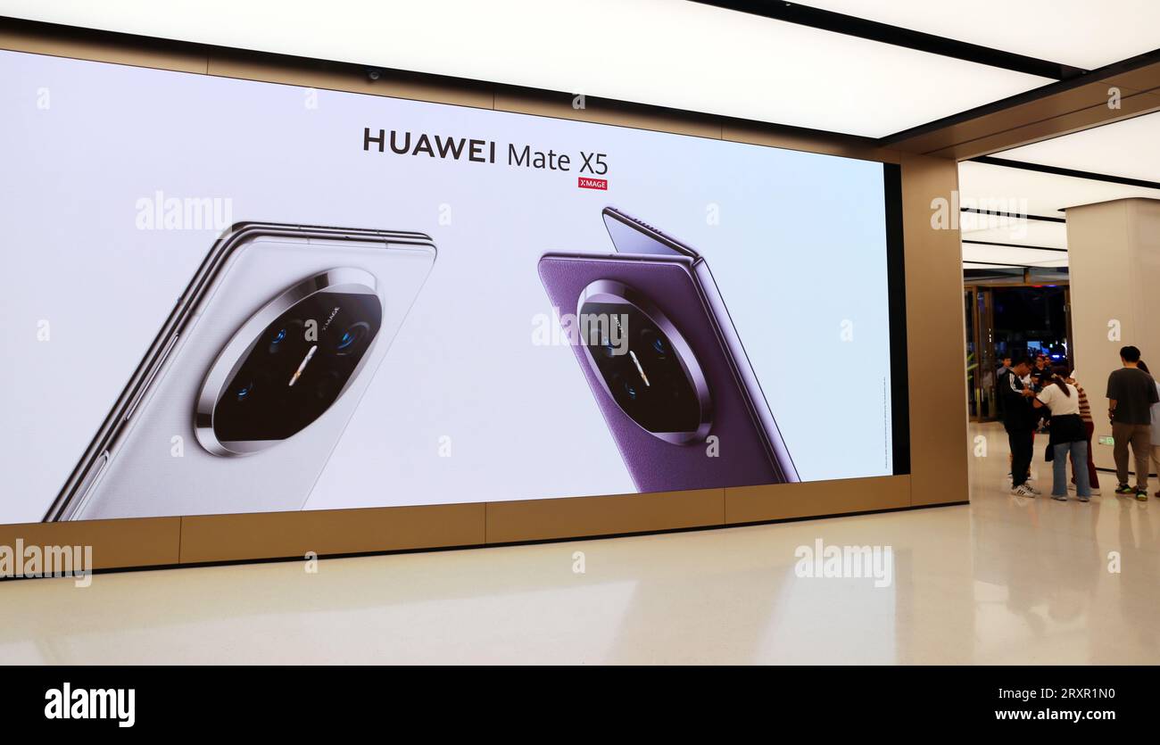 SHANGHAI, CHINA - SEPTEMBER 24, 2023 - Visitors pass a poster of Huawei ...