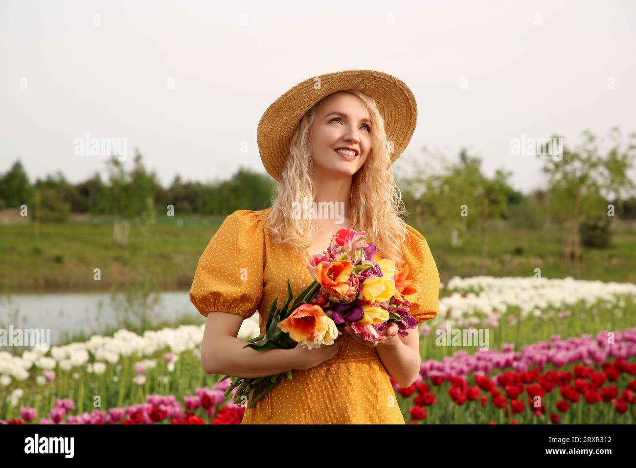 Happy woman with spring bouquet of flowers in beautiful tulip field on ...
