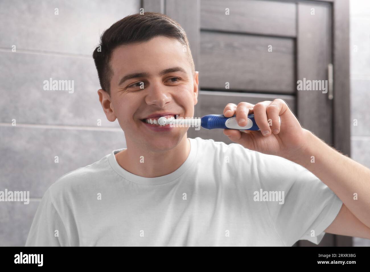 Man brushing his teeth with electric toothbrush indoors Stock Photo - Alamy