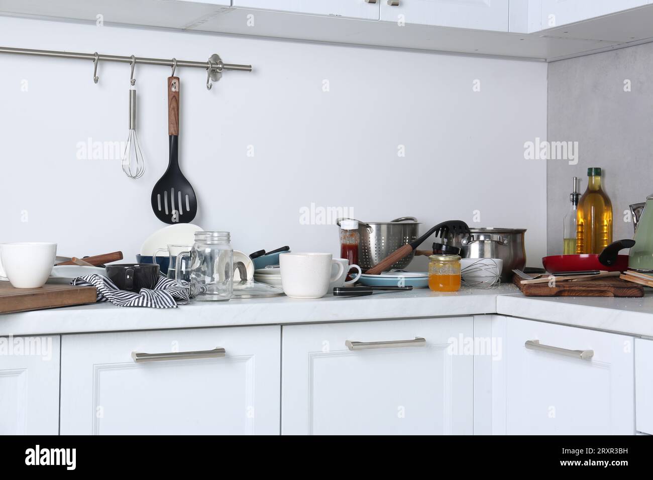 Many dirty utensils, cookware and dishware on countertop in messy ...