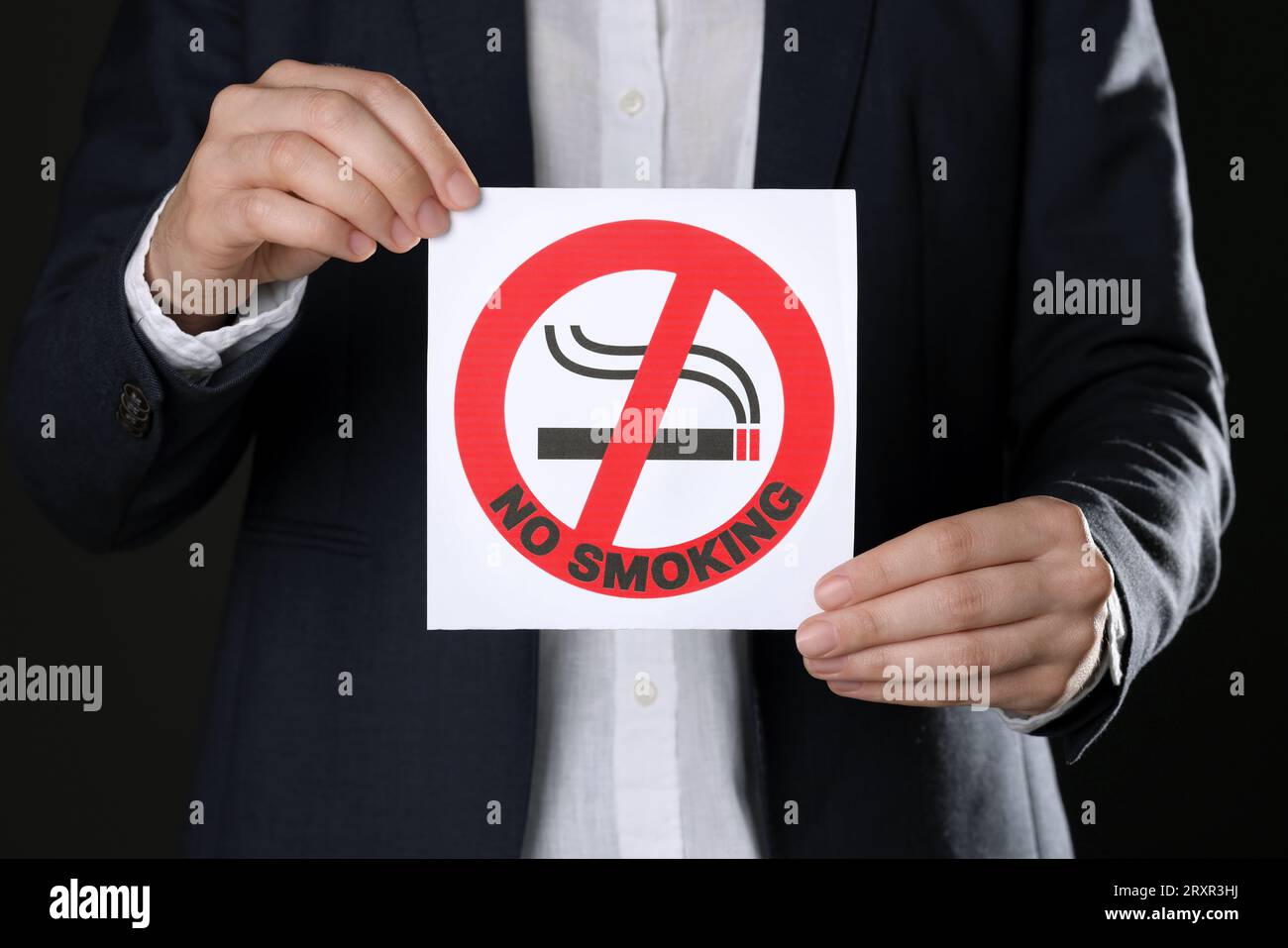 Woman holding card with no smoking sign on black background, closeup ...