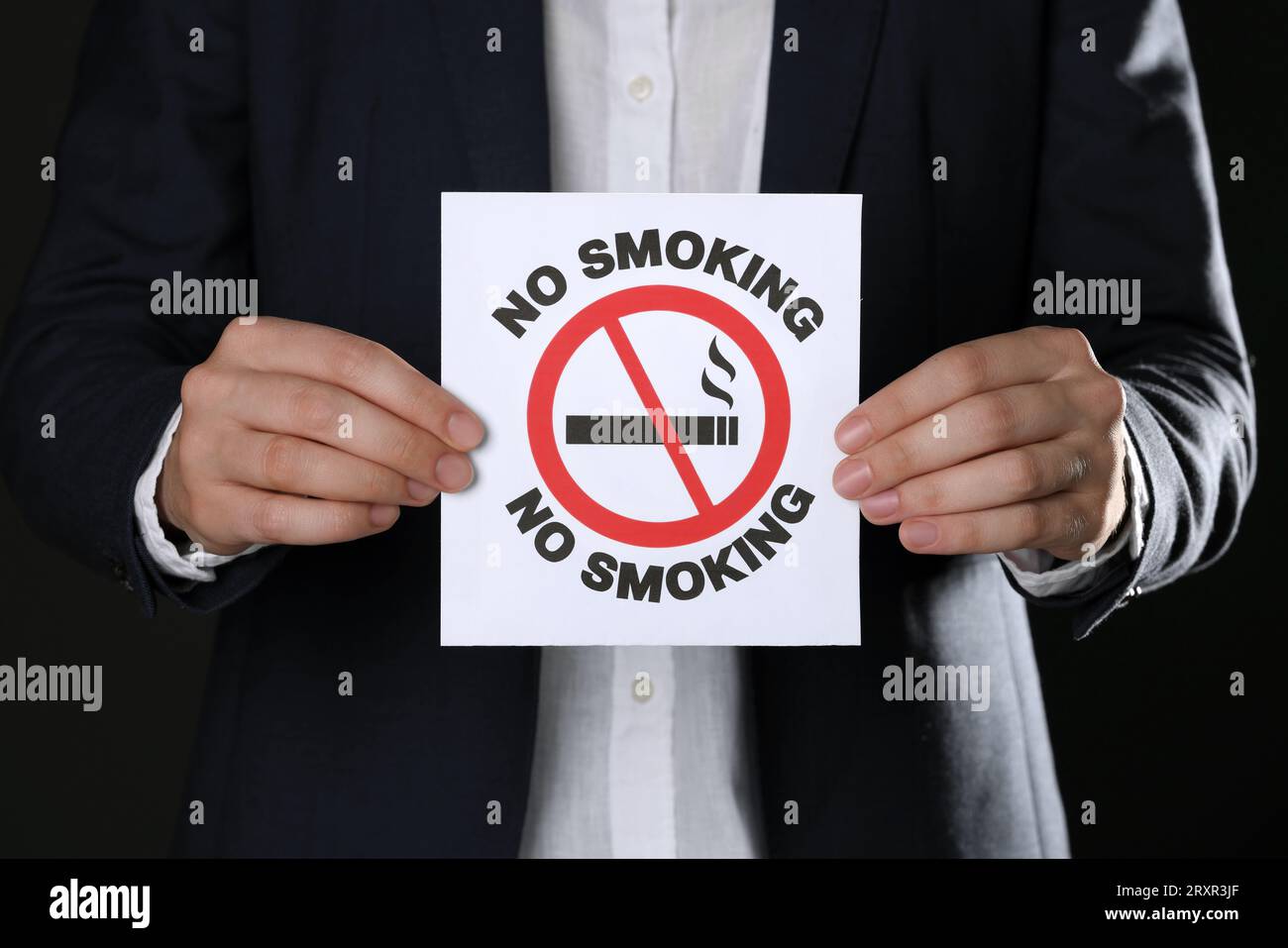 Woman holding card with no smoking sign on black background, closeup ...