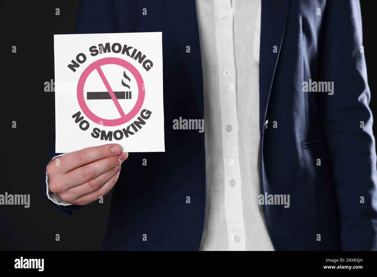 Woman holding card with no smoking sign on black background, closeup ...