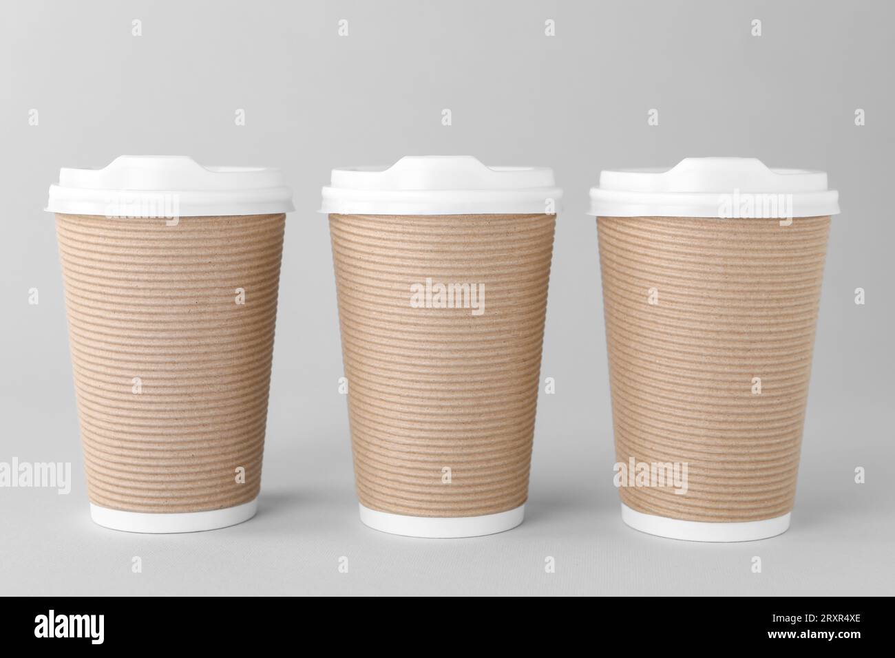 Paper cups with white lids on light grey background. Coffee to go Stock ...