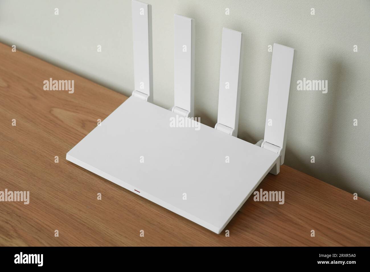 New modern Wi-Fi router on wooden table near white wall Stock Photo - Alamy