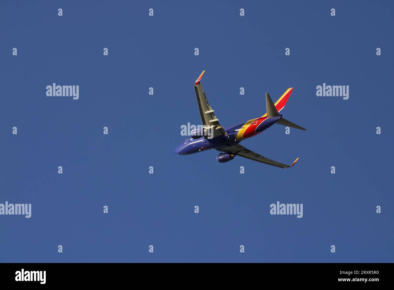 Southwest 737 flying against cloudless blue sky, underbelly view Stock ...