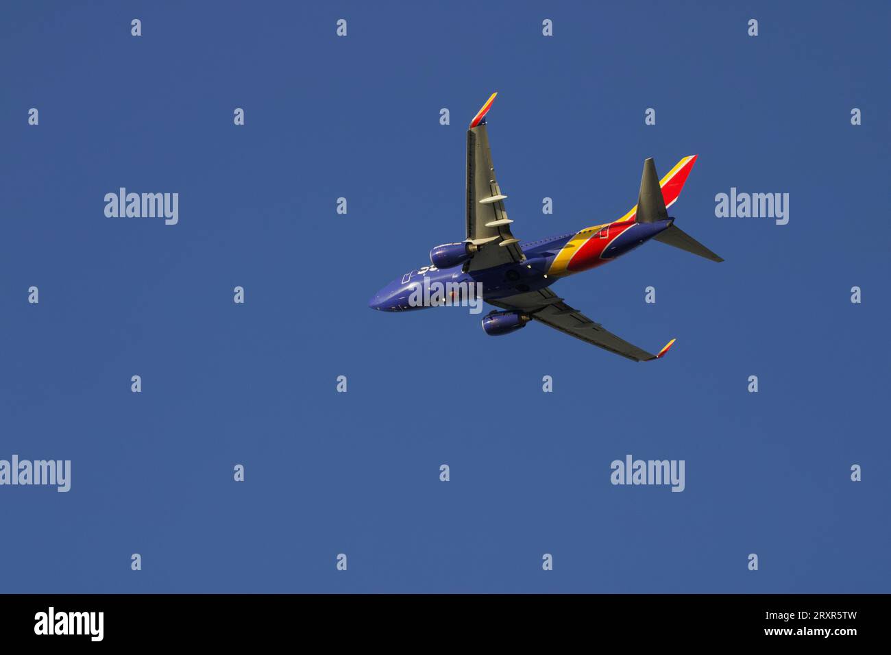 Southwest 737 flying against cloudless blue sky, underbelly view Stock ...