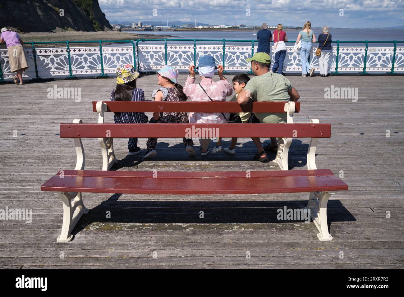 Family sitting on bench on the Pier at Penarth in Glamorgan South Wales ...