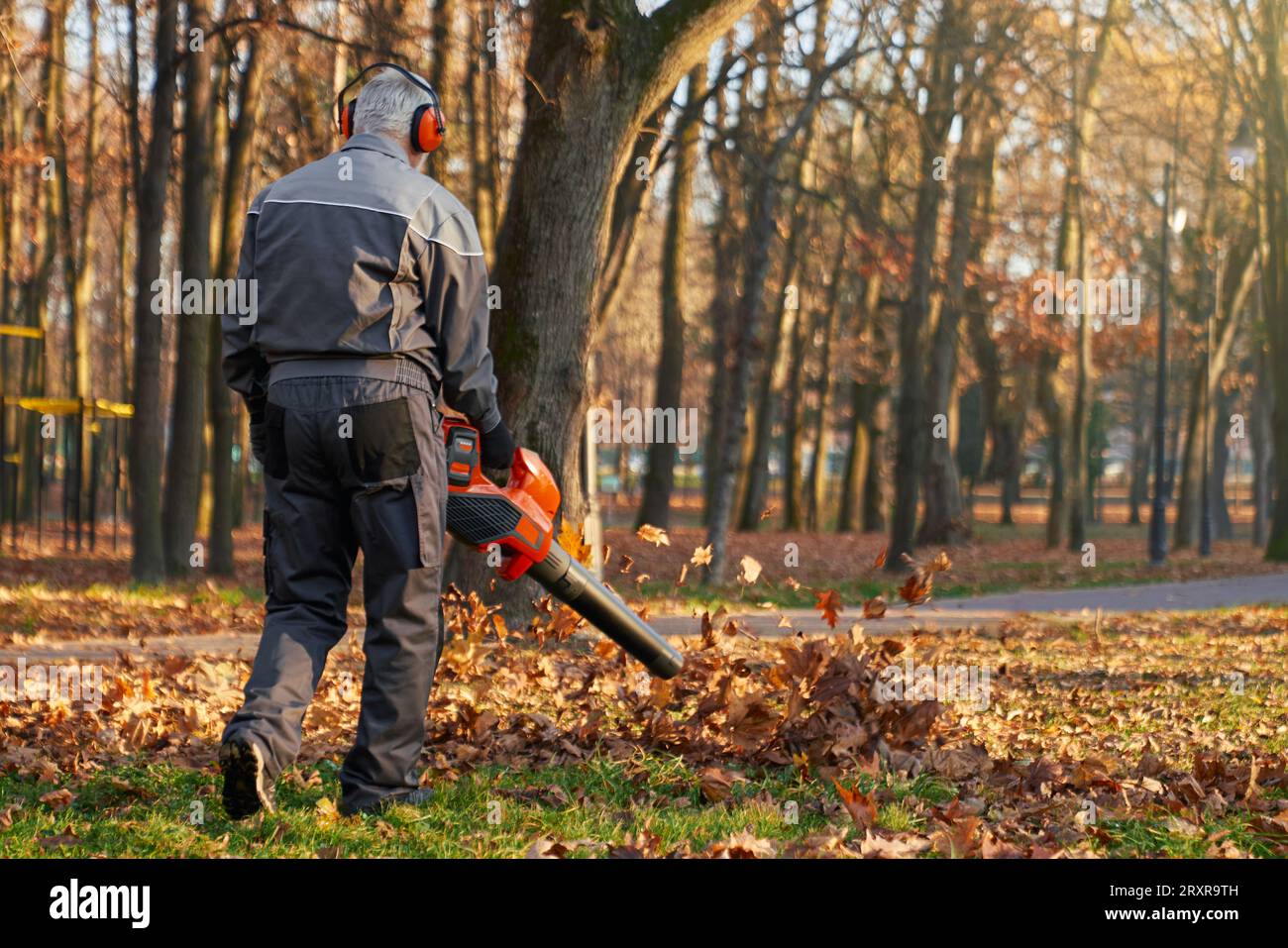 Anonymous male municipal worker cleaning up resting area in autumn day ...