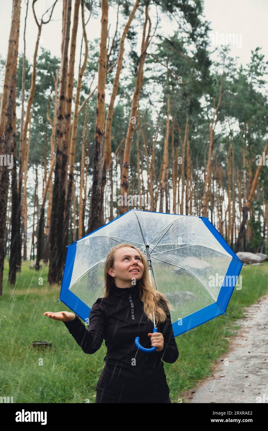 Blonde girl checking the weather under transparent umbrella outside in ...