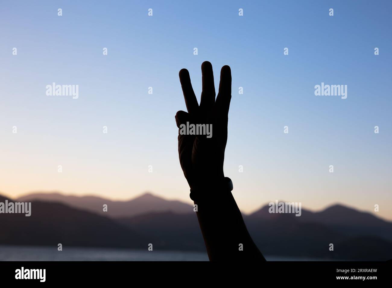 silhouette of hands in the shape of the number three with a beautiful ...